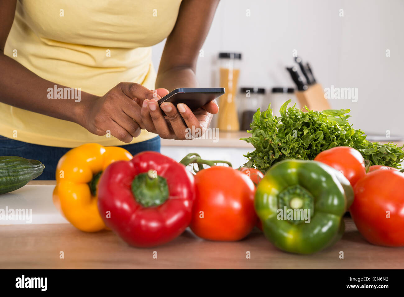 Close-up Of A Woman Using Mobile Phone With Vegetables In Kitchen Stock ...