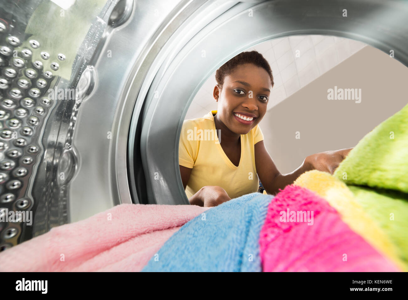 Young African Woman Putting Clothes Into Washing Machine At Home Stock ...
