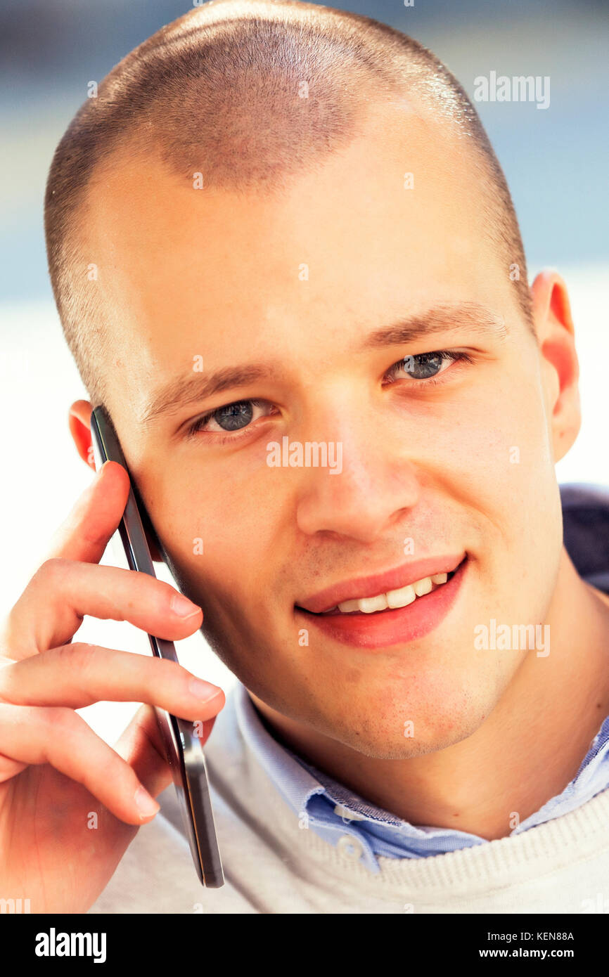 Close up portrait of a cheerful handsome young man talking on phone and ...