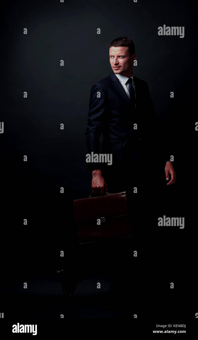 Portrait of a handsome business man with briefcase isolated on black ...