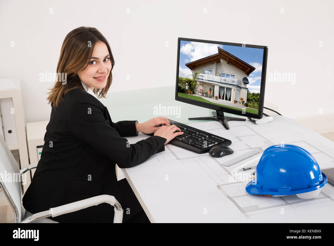 Young Female Architect Looking At Designs Of House On Computer In ...