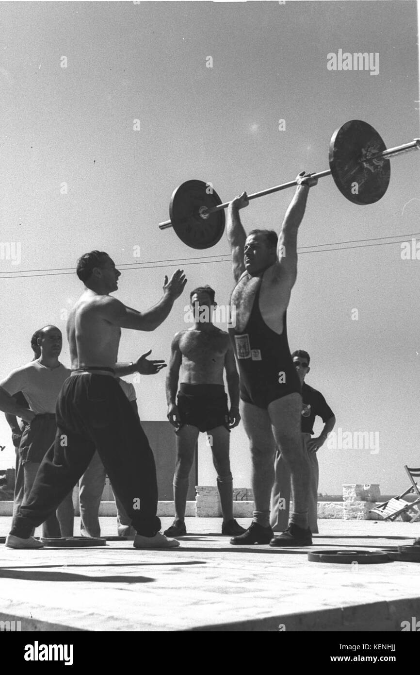 This image depicts a British coach providing weight lifting tips ...