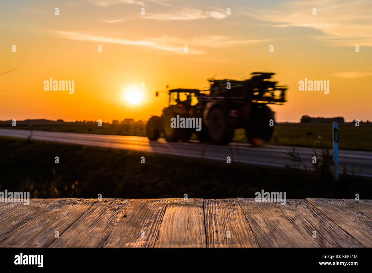 Empty rustic wood table top with tractor silhuette at sunset background ...