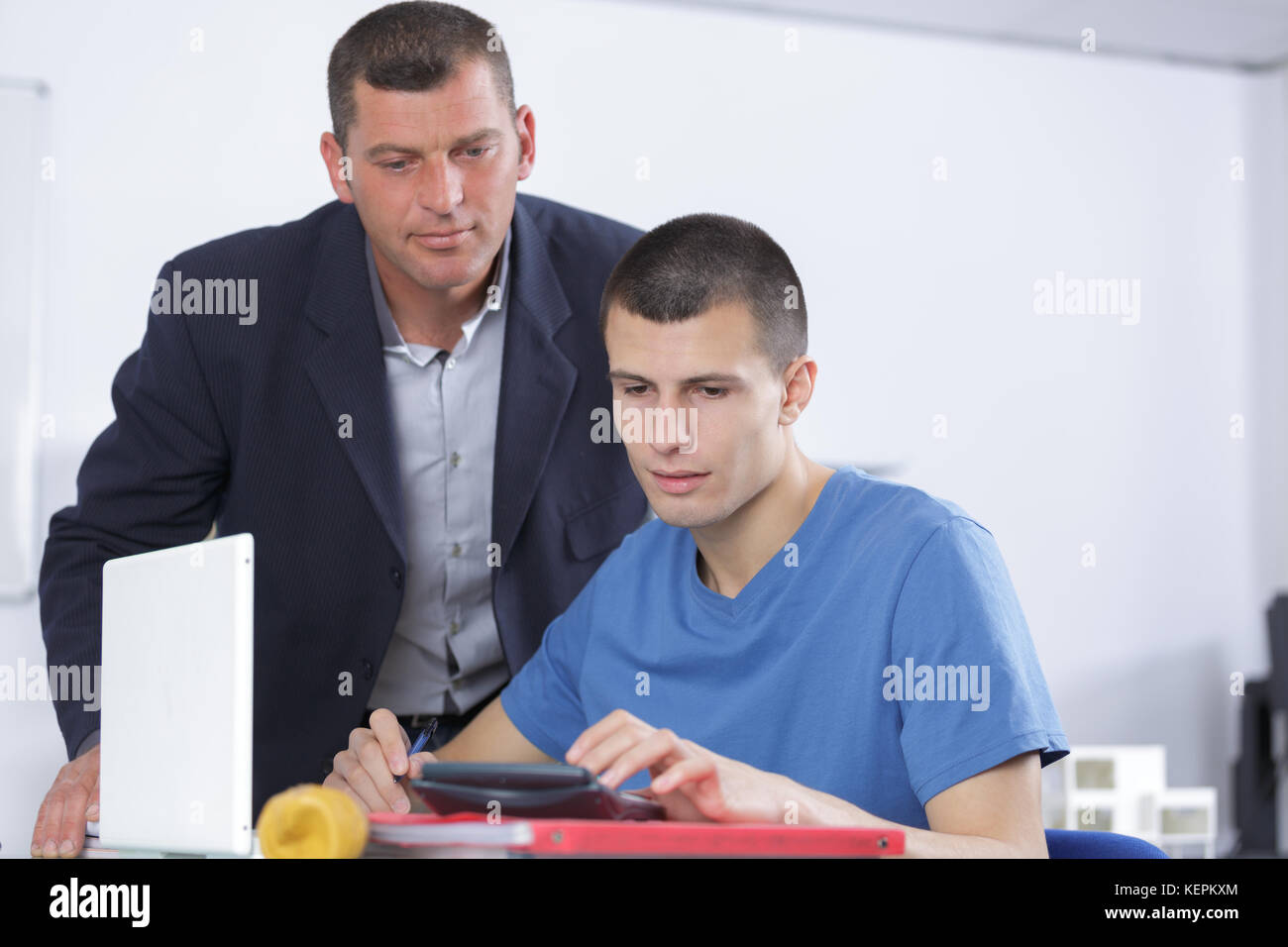 male teacher explaining topic on laptop to student Stock Photo - Alamy