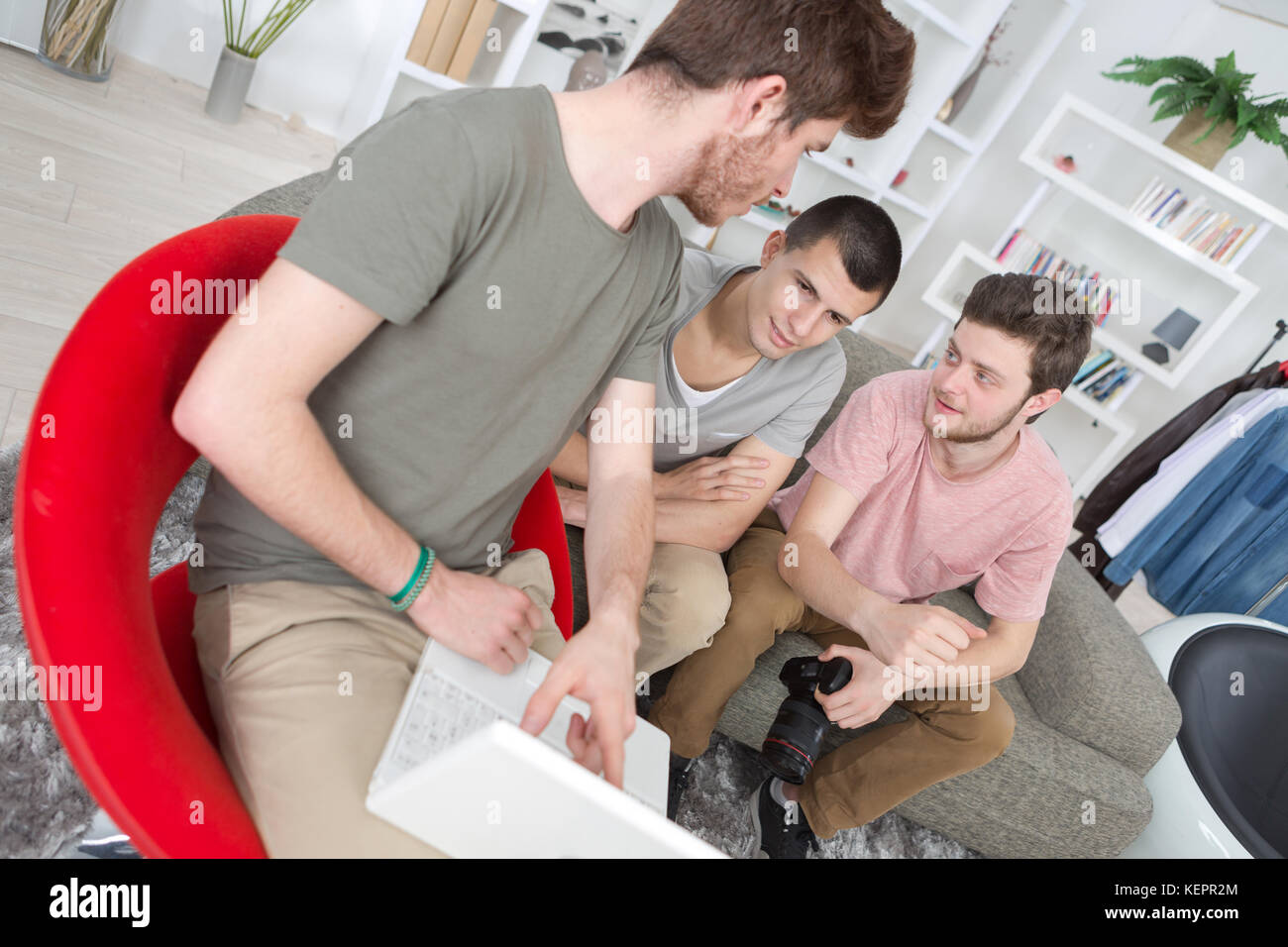 Three young men with camera and laptop Stock Photo - Alamy