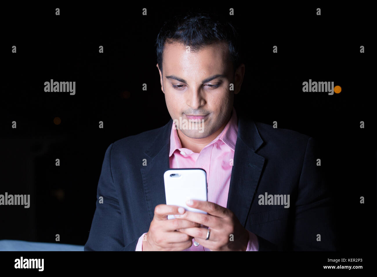 Closeup portrait, young man in black blazer, pink shirt using cell ...