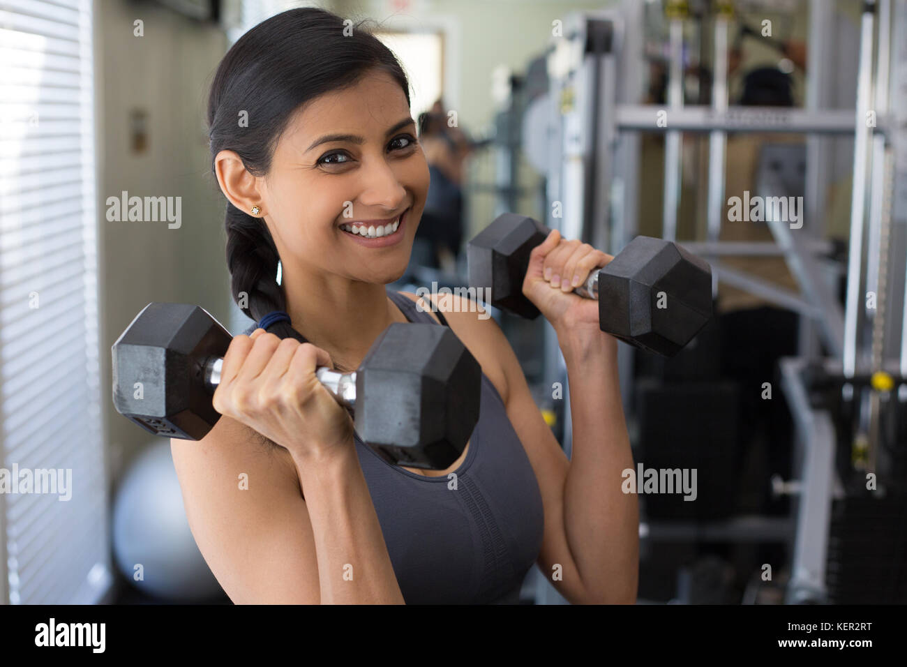 Closeup portrait, young attractive woman lifting weight in gym, indoors ...