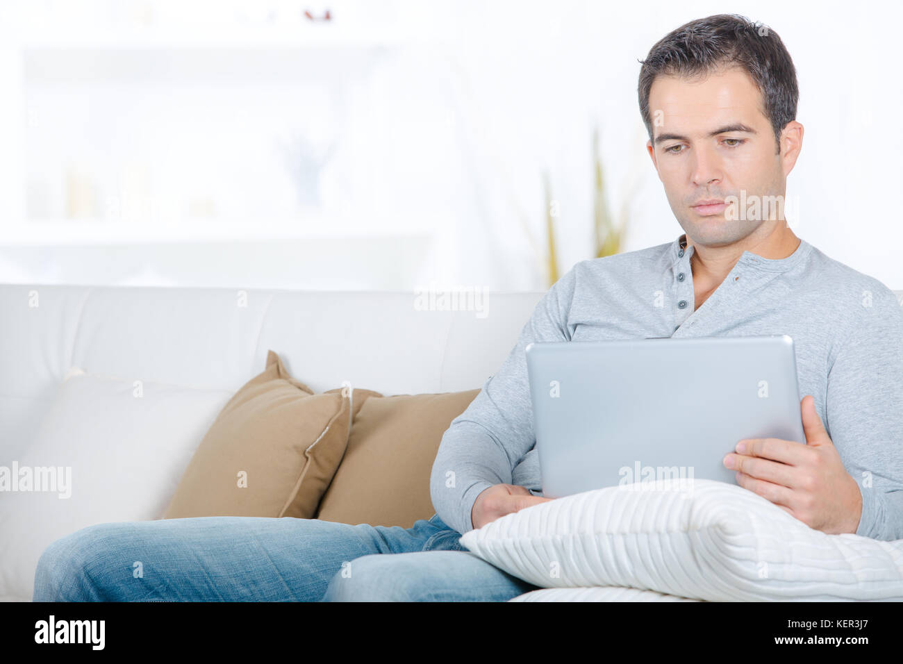 man using laptop while sitting at home on the sofa Stock Photo - Alamy