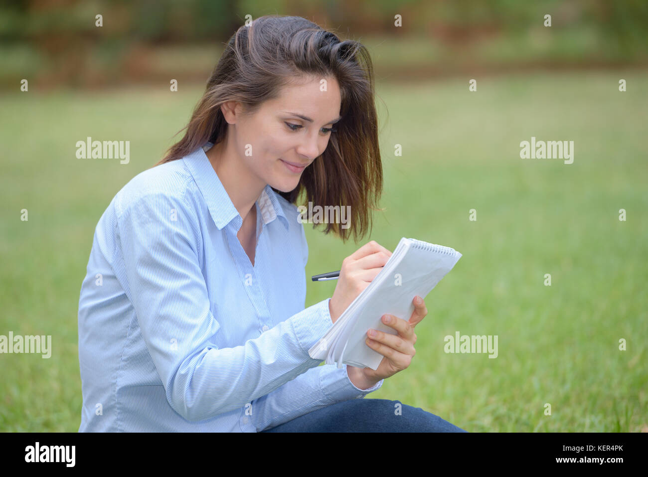 Lady writing, sat on grass Stock Photo - Alamy