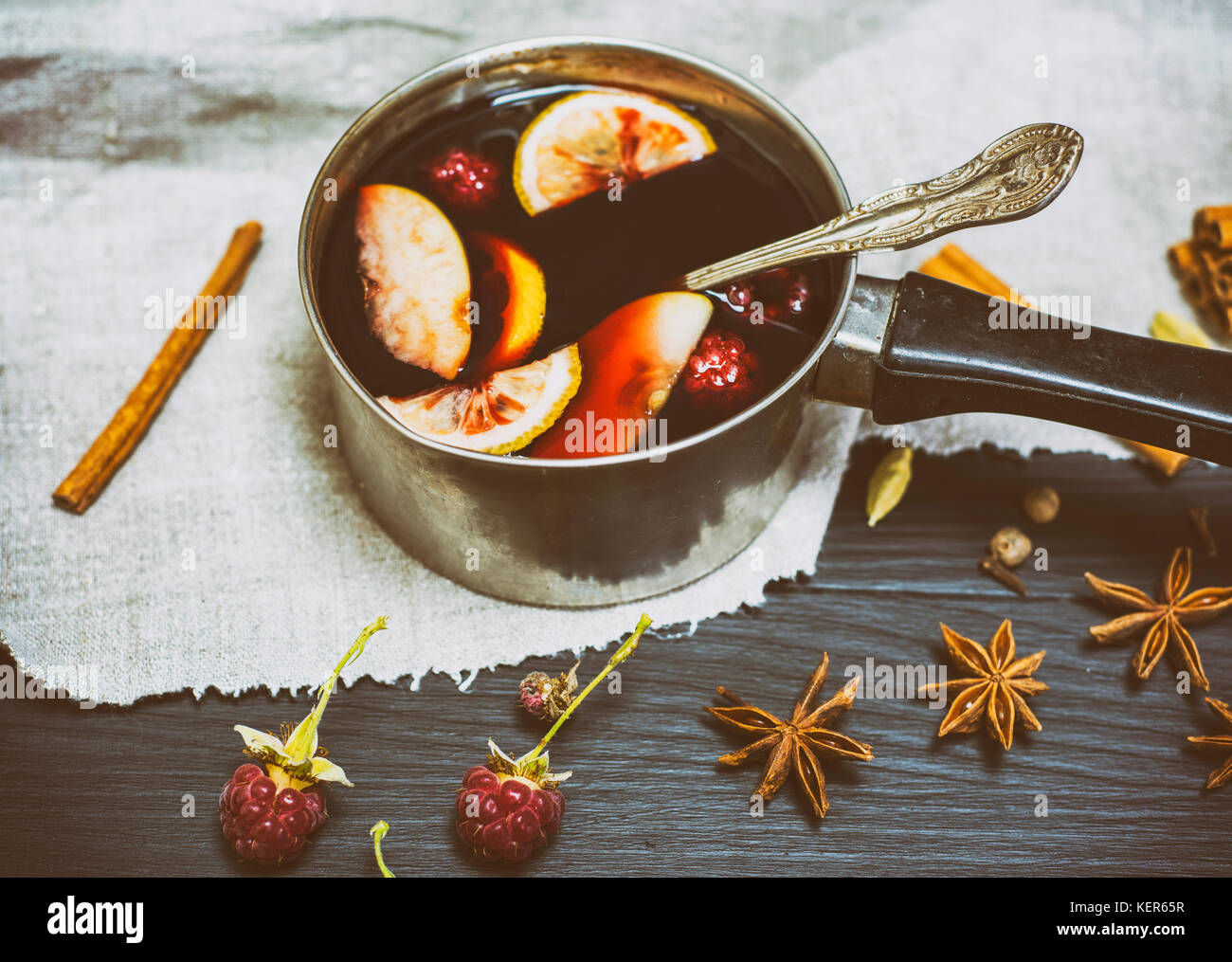 mulled wine in an aluminum ladle with a handle on a black background ...