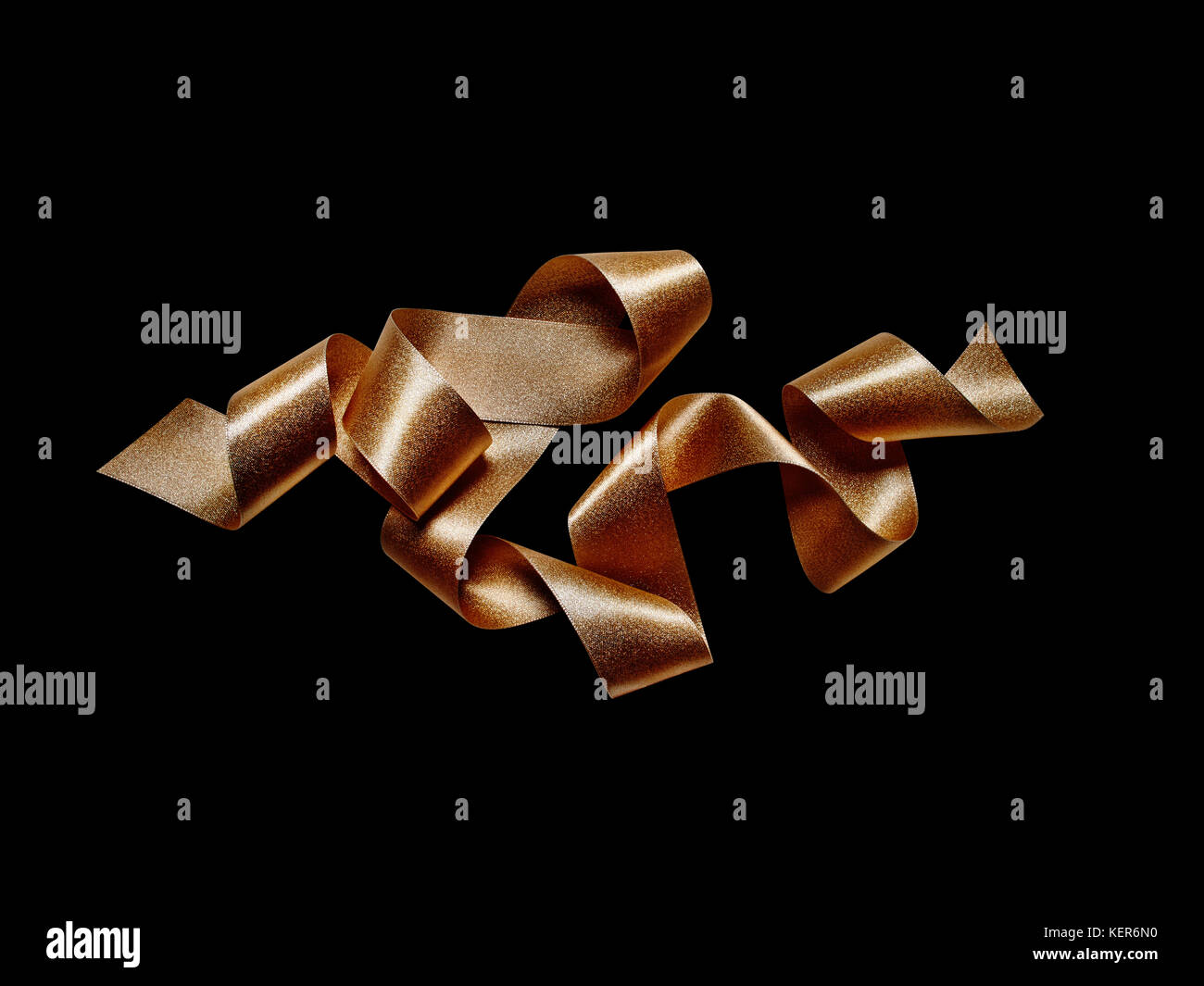 Close up of gold bronze metallic ribbon isolated on black background ...