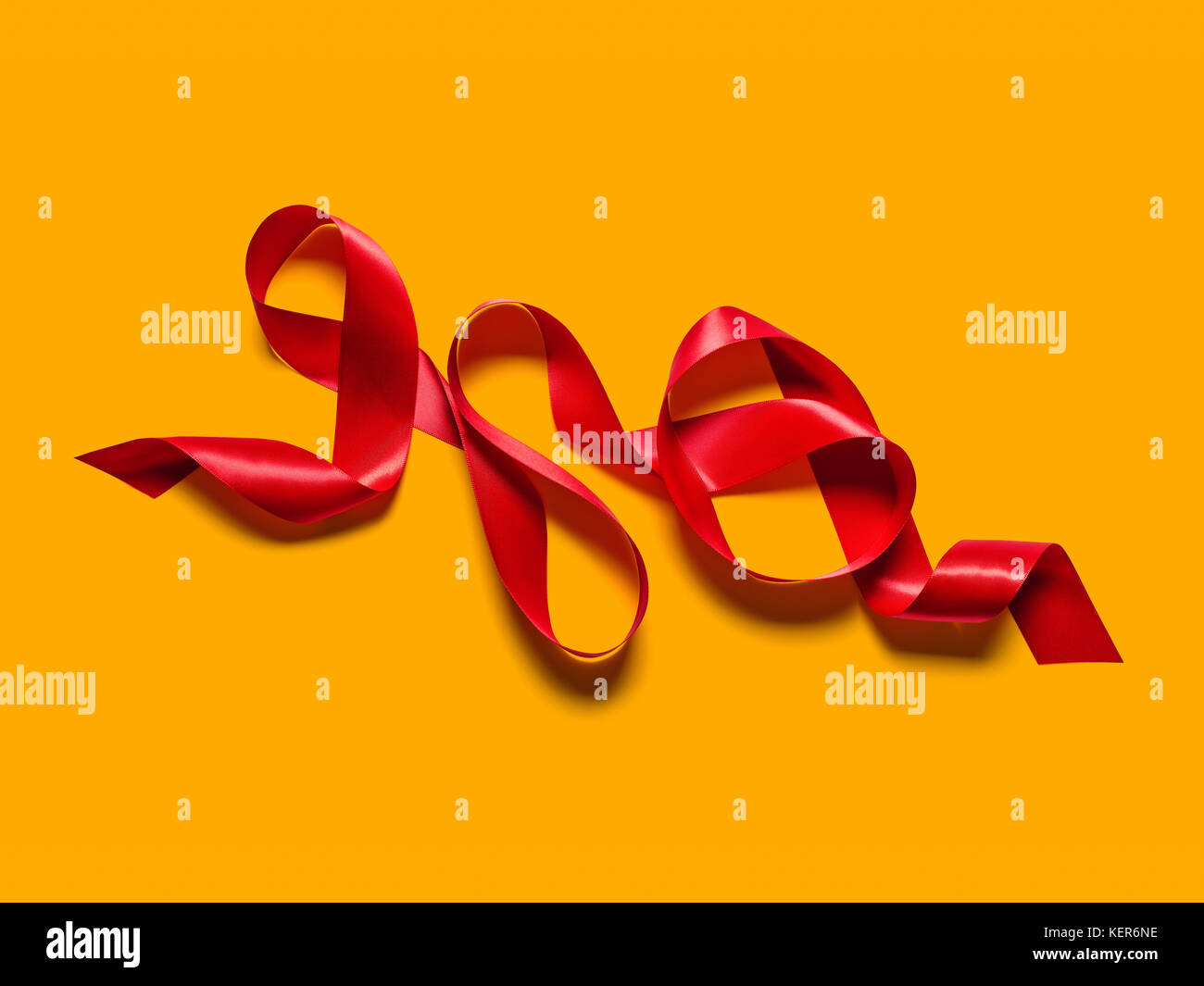 Red satin silk ribbon isolated on yellow background Stock Photo - Alamy