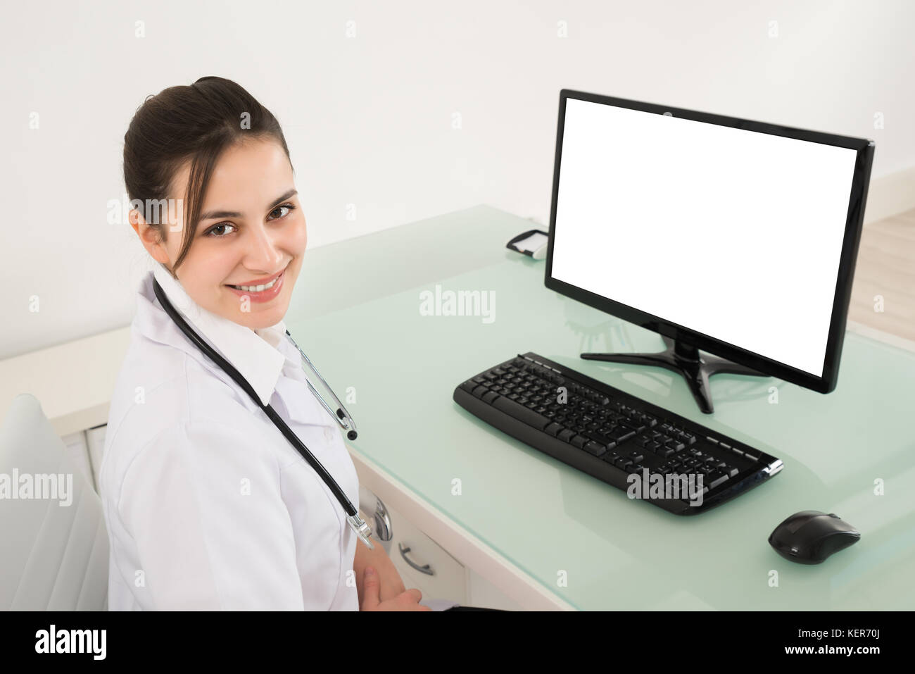 Happy Female Doctor Sitting In Front Of Computer In Clinic Stock Photo ...