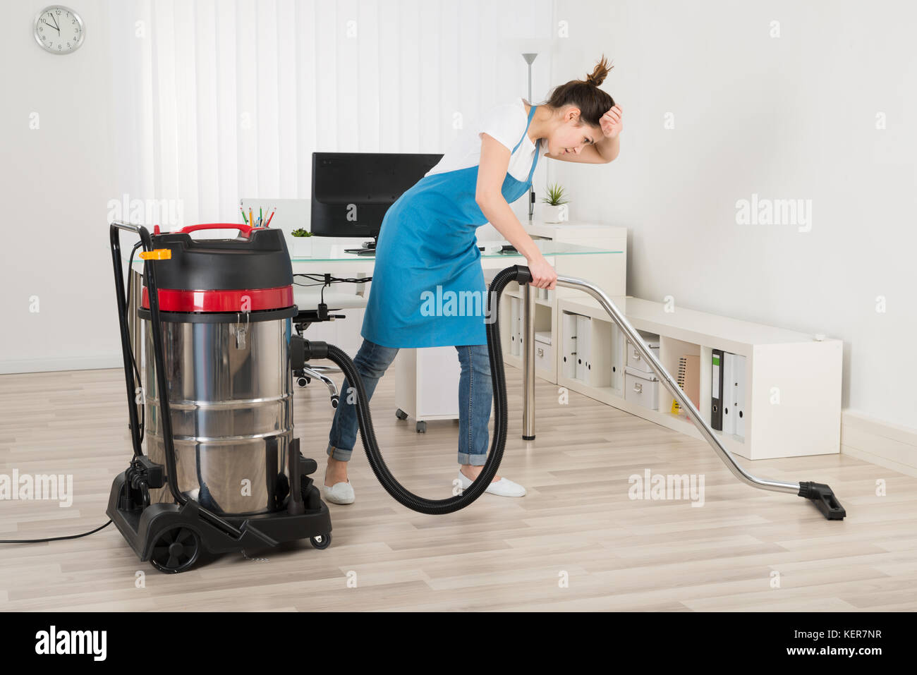Tired Young Female Janitor Cleaning Floor With Vacuum Cleaner Stock ...