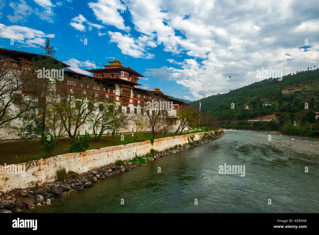 A massive Buddhist monastery on the shore of a turquoise alpine river ...