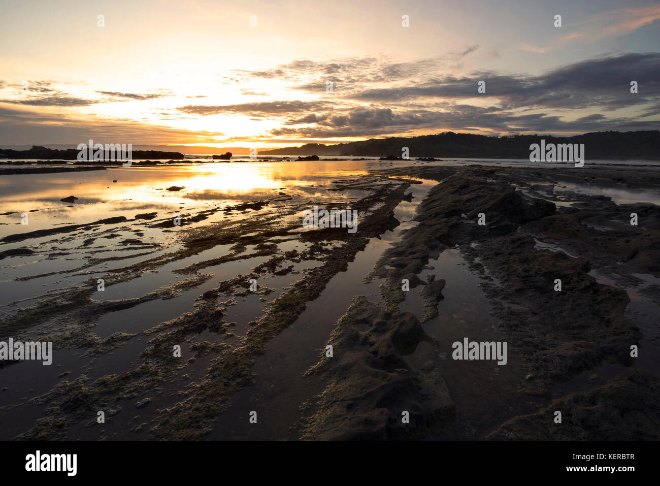 Beautiful view of sawarna beach with rocks and calm waves at sunset ...