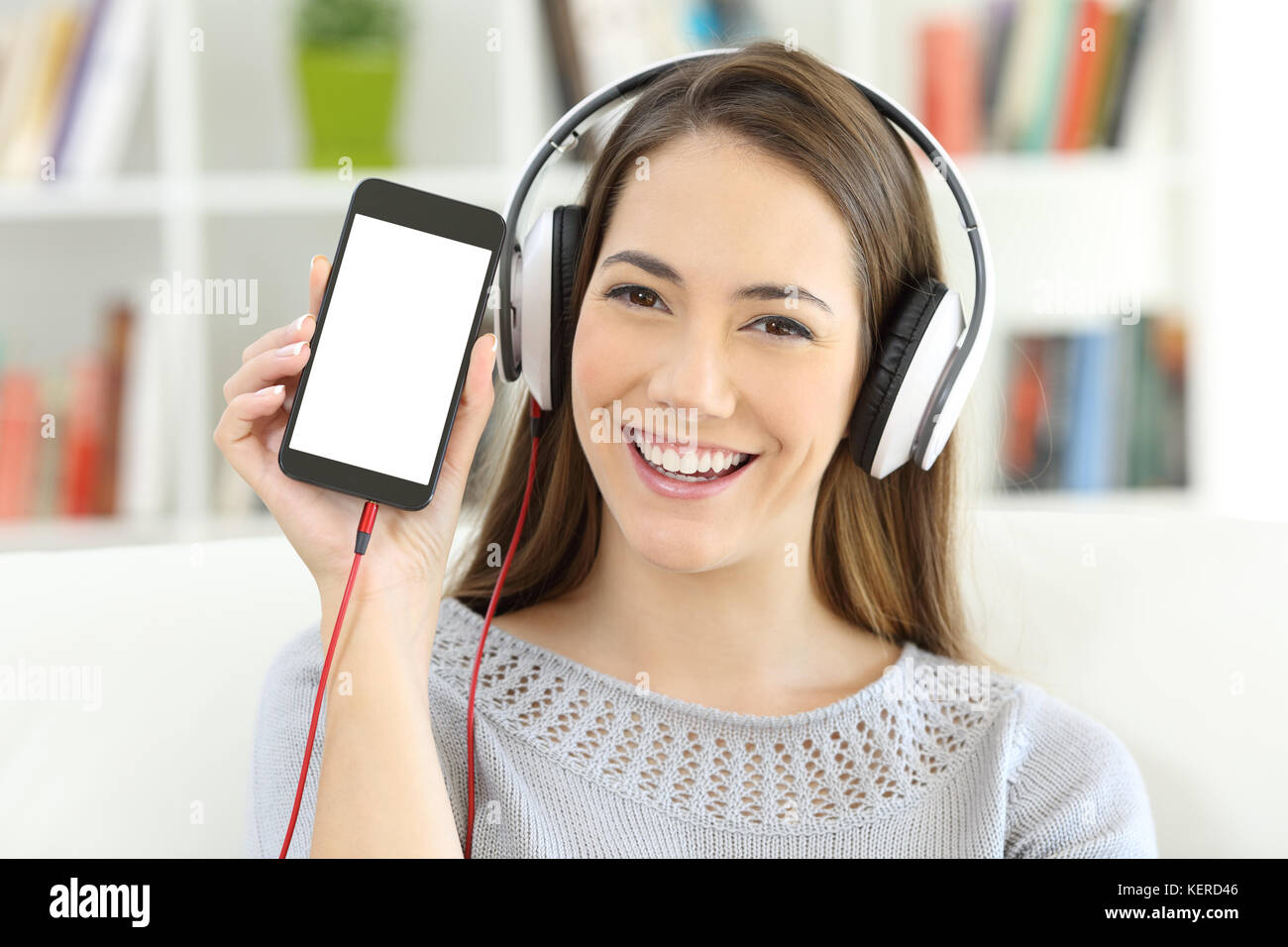 Front view portrait of a happy girl listening to music and showing a ...