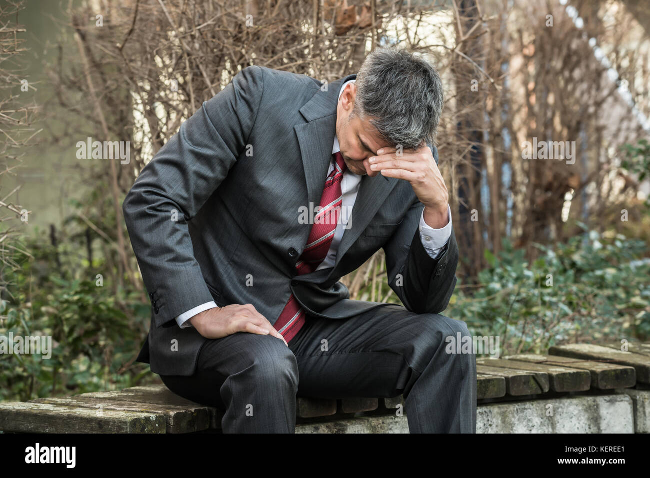 Sad Businessman Sitting On The Bench Outdoors And Having Headache Stock ...