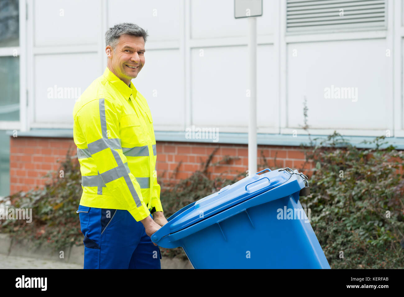Happy Male Worker Walking With Dustbin On Street During Day Stock Photo ...