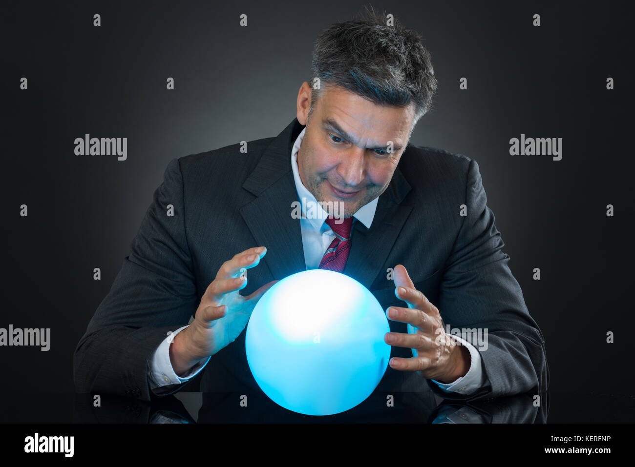 Portrait Of Businessman Predicting Future With Crystal Ball On Desk ...