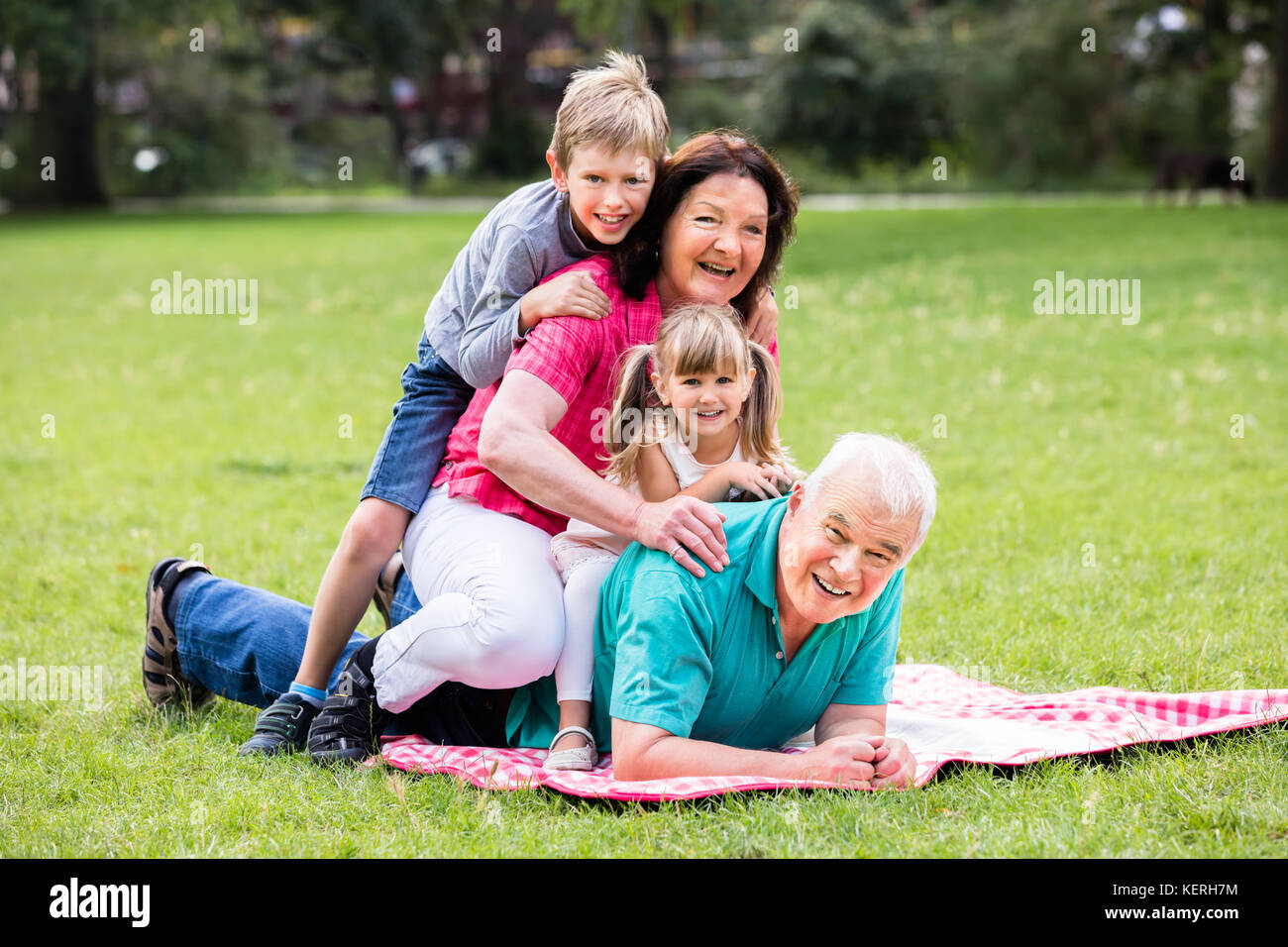 Happy Family Having Fun Lying On Grass In Park Stock Photo - Alamy