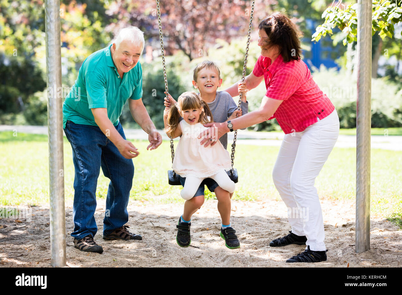 Senior Grandparents Having Fun With Kids On Swing In The Park Stock ...