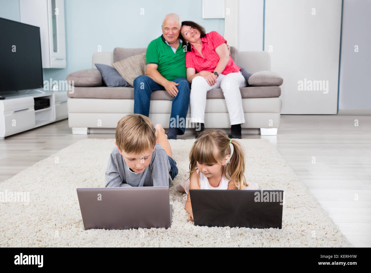 Happy Kids Playing With Laptop Computer In Front Of Family Stock Photo ...