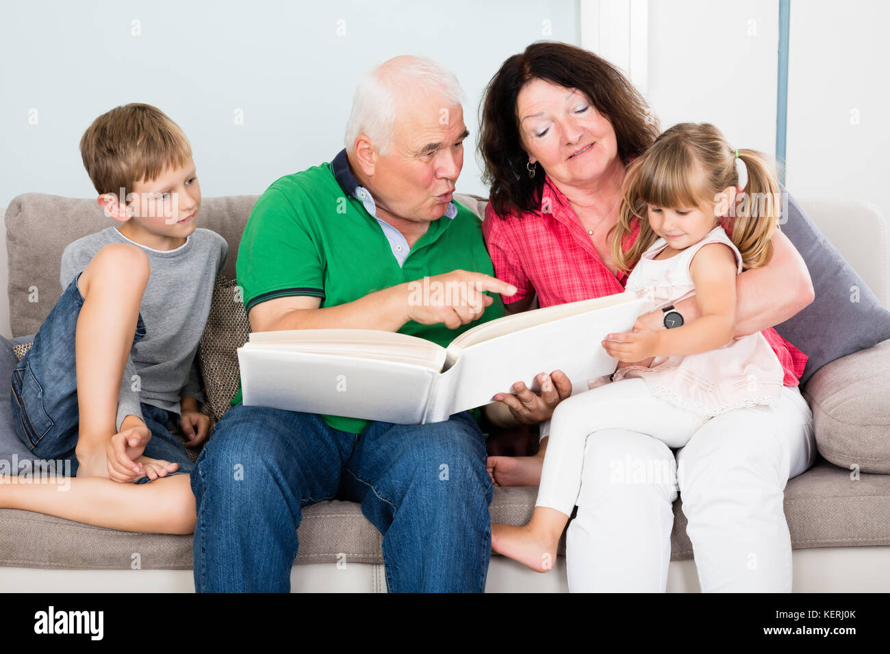 Family Looking At Photo Album With Children To Refresh Memory Stock ...