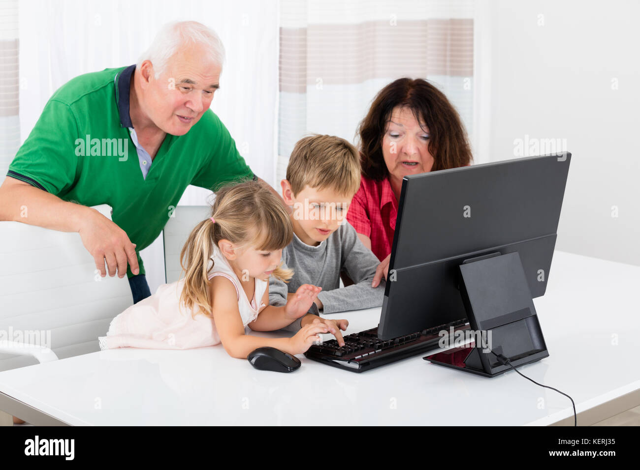Happy Older Grandparents Using Laptop Computer With Children At Home ...