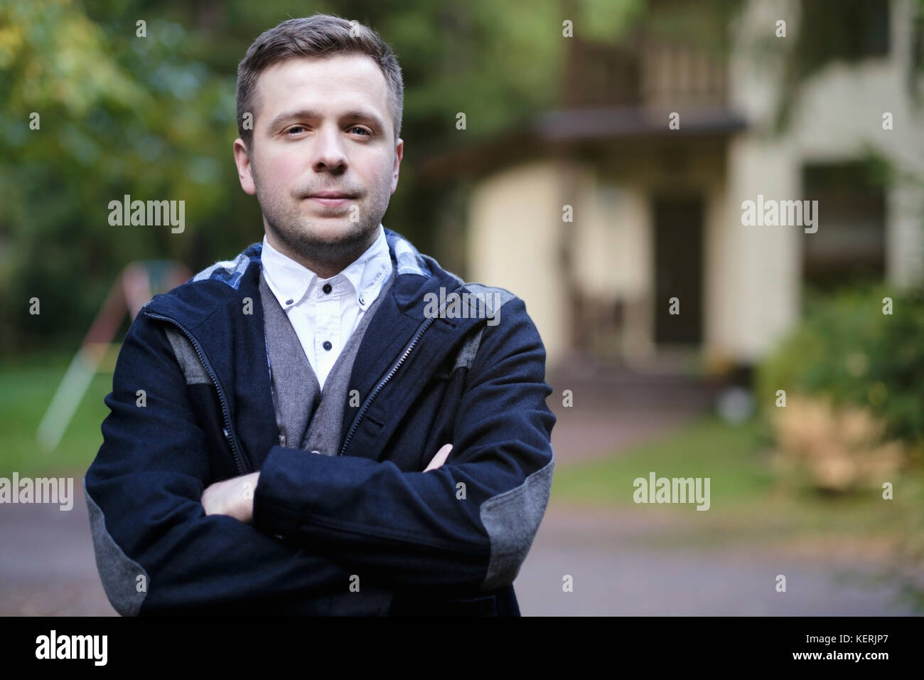 A successful and handsome young man stands next to the house bought ...