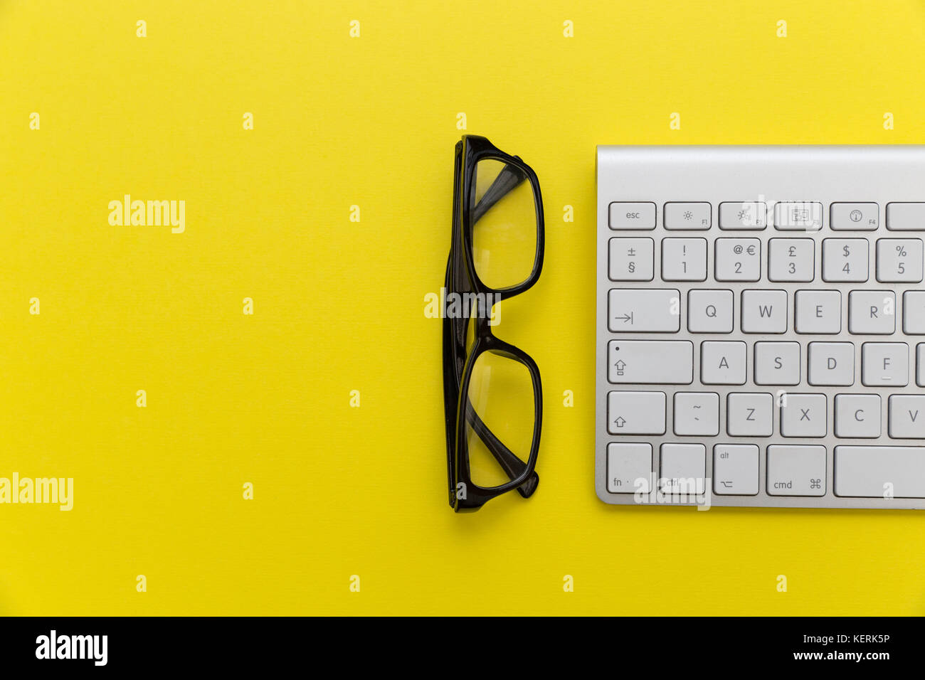 Computer keyboard and reading glasses on bright yellow background Stock ...