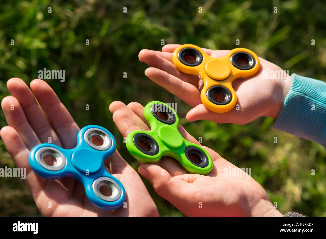 Spinner of different colors lie in the hands of children against the ...