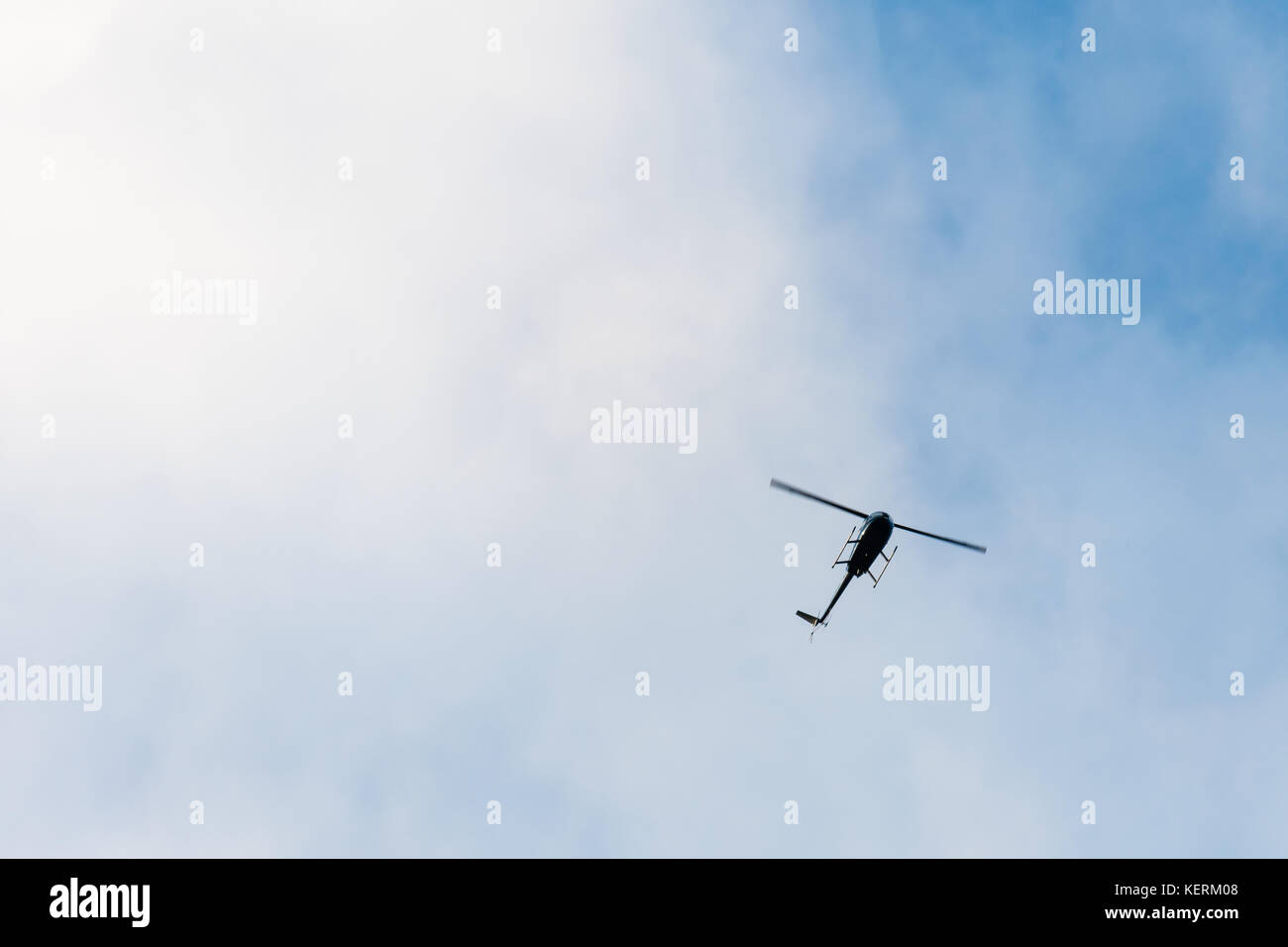 The helicopter on the blue sky with clouds. The view from bottom to the ...