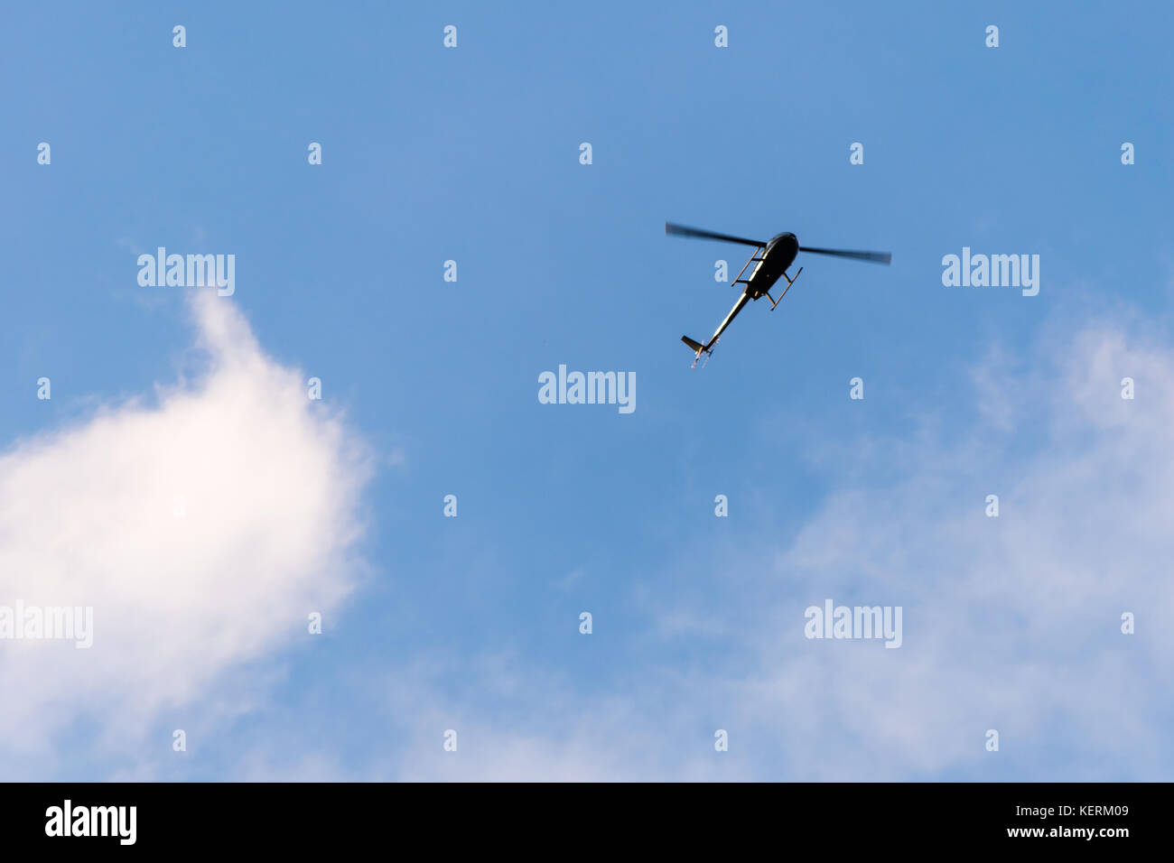 The helicopter on the blue sky with clouds. The view from bottom to the ...