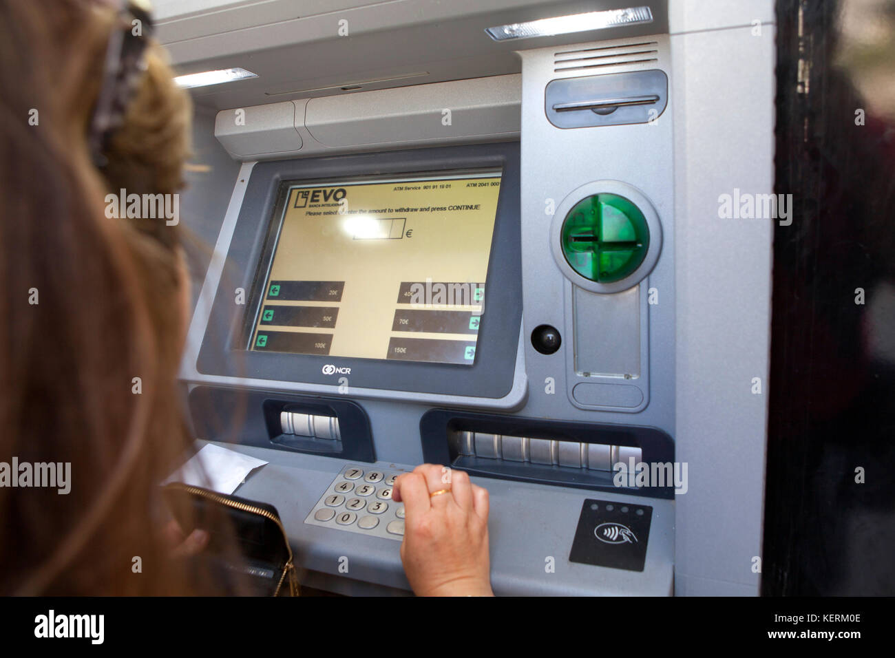 Woman withdrawing cash at an ATM cash machine in Spain, Europe Stock ...