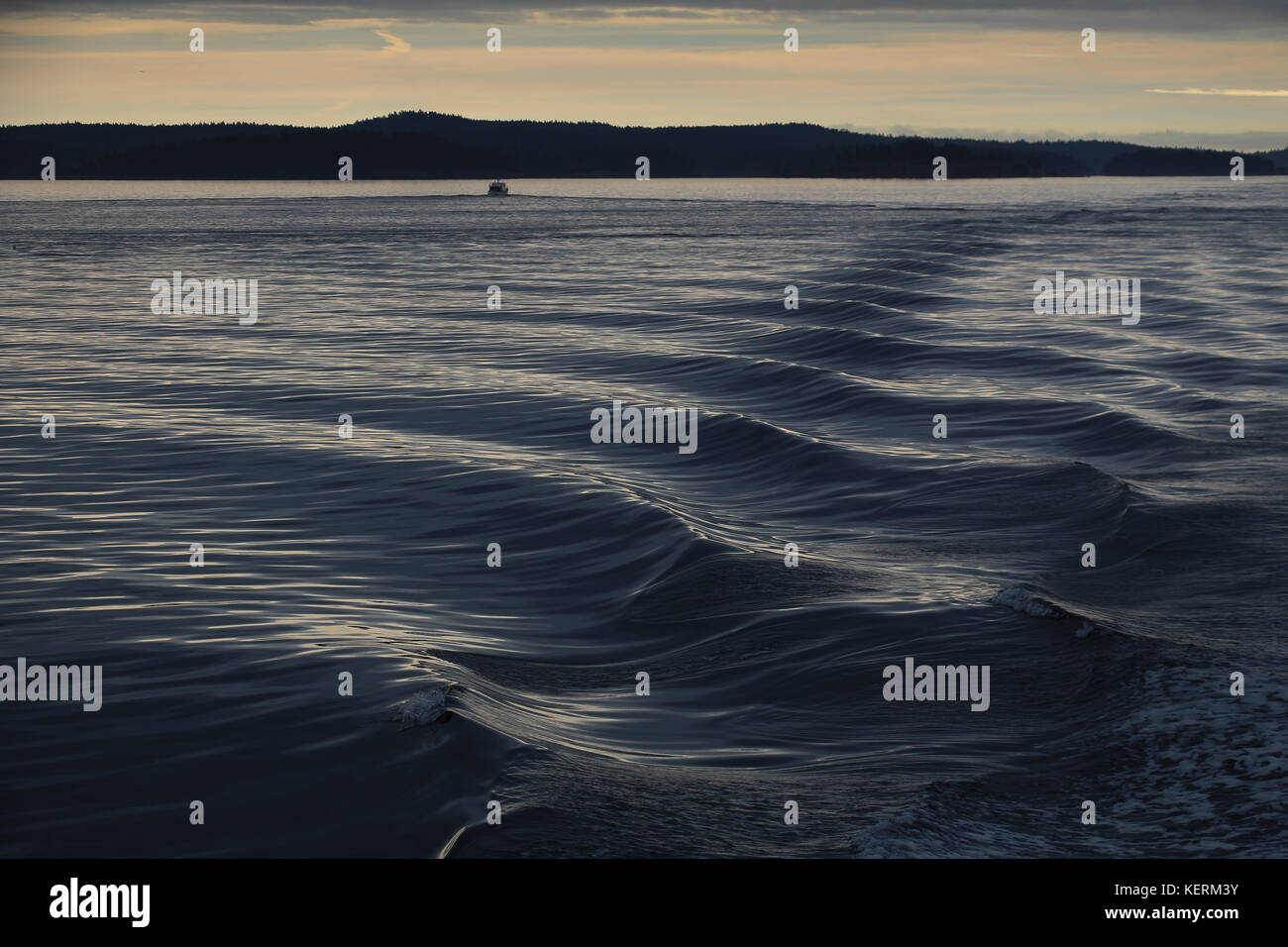 Early morning sailing, a distant boat has created a wake that reflects ...