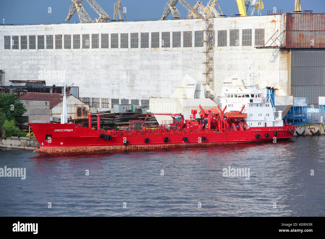 Red cargo ship in the port. Containers with goods are loaded / unloaded ...