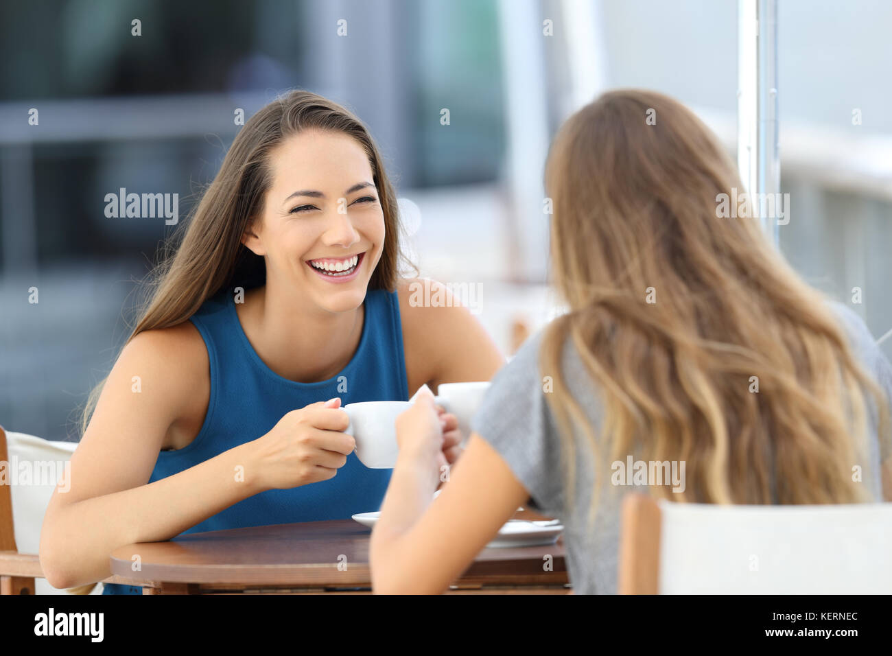 Two happy friends talking and laughing sitting in a restaurant terrace ...