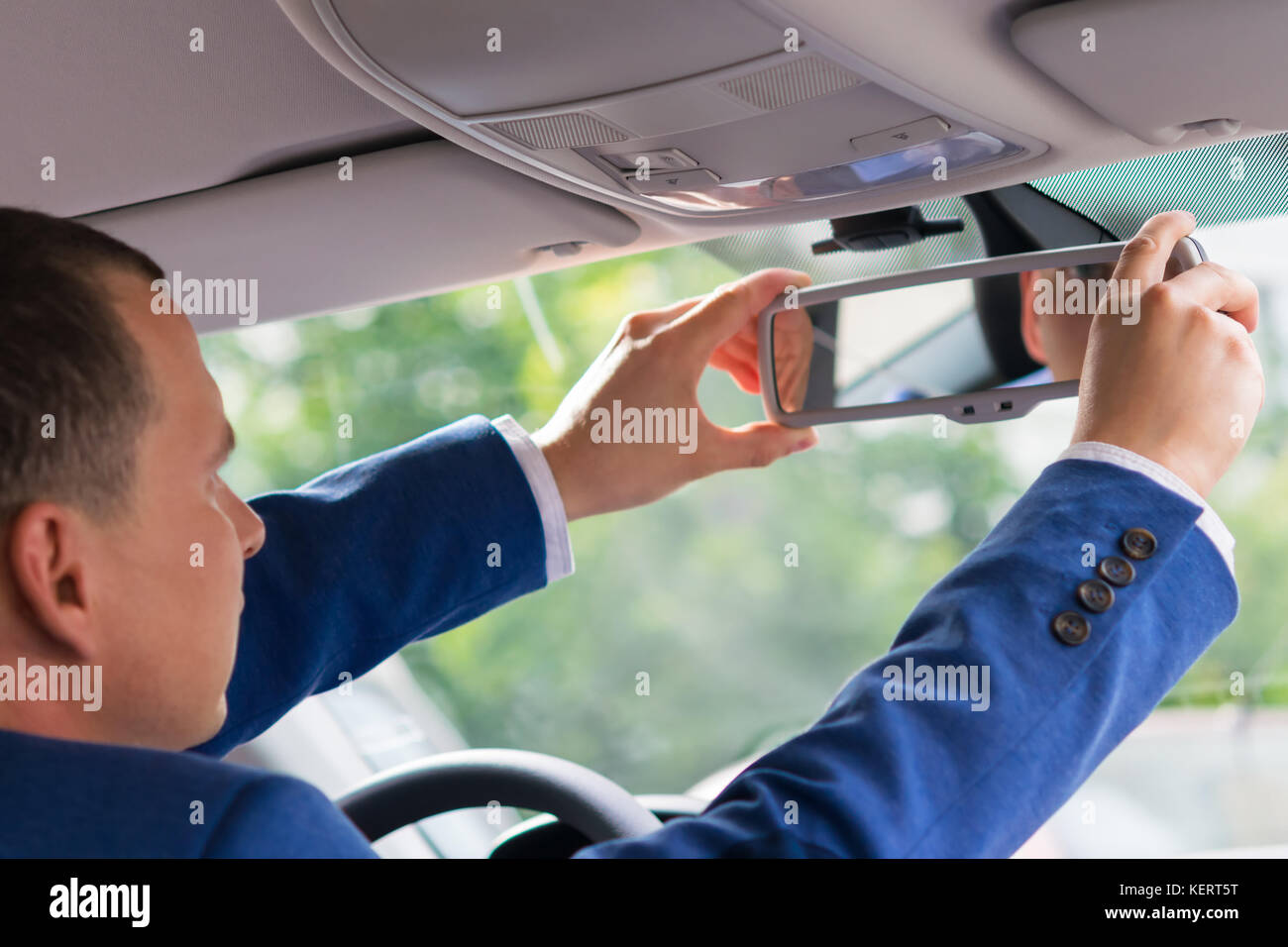 driver businessman adjusts rear view mirror in car interior Stock Photo ...