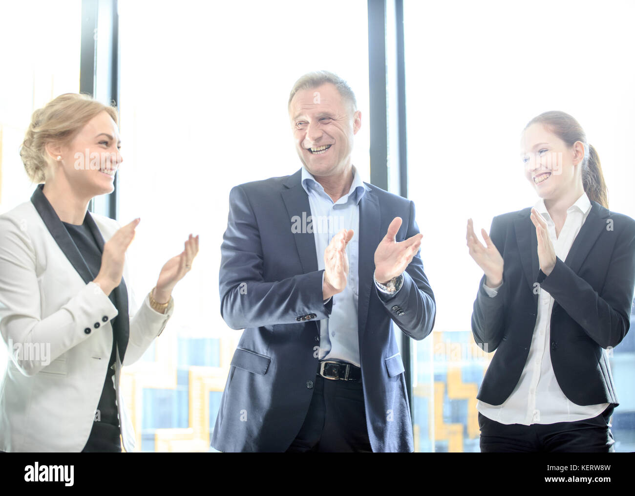 Business people group clapping and smiling in office standing around ...