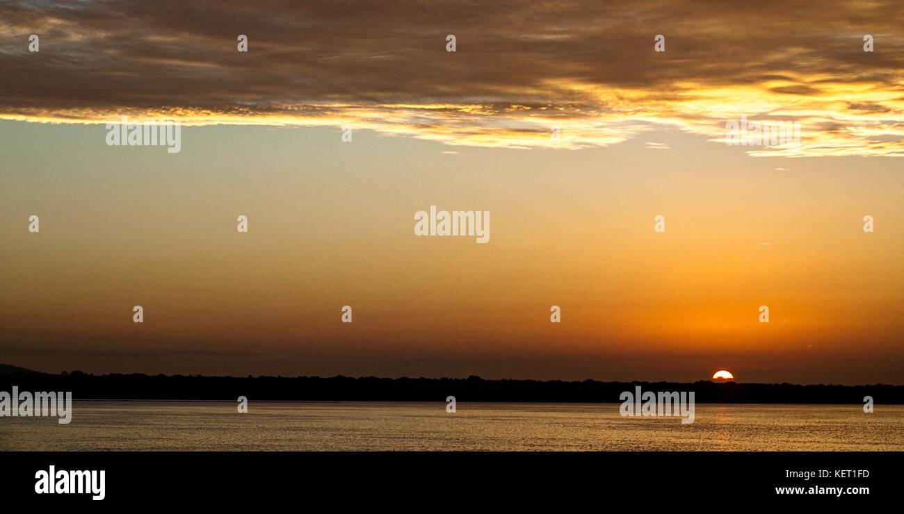 A vibrant gold coloured cloudy sea water sunrise seascape with ocean ...
