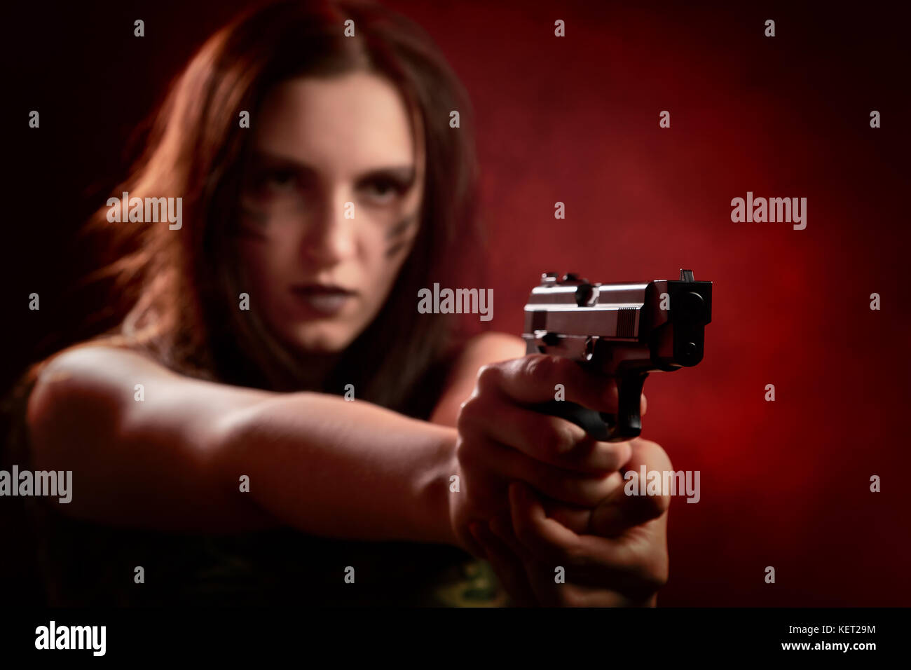serious young woman with gun aiming on red background Stock Photo - Alamy