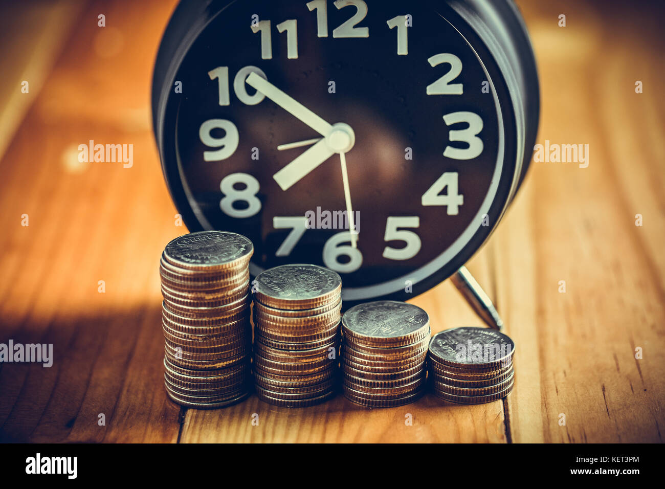 Alarm clock and step of coins stacks on working table, time for savings ...