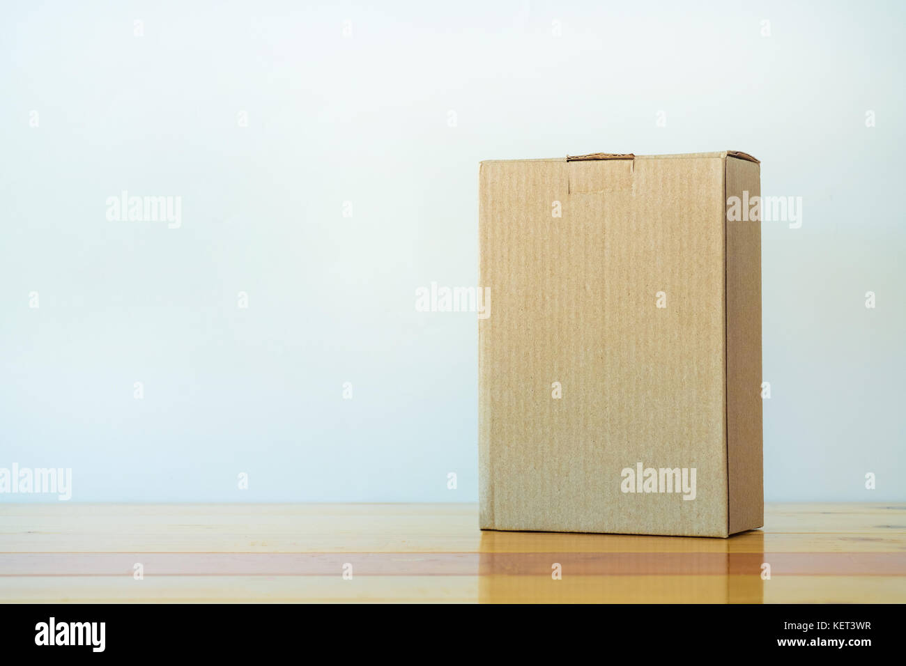 Empty closed brown cardboard box for mock up on bright wooden table ...
