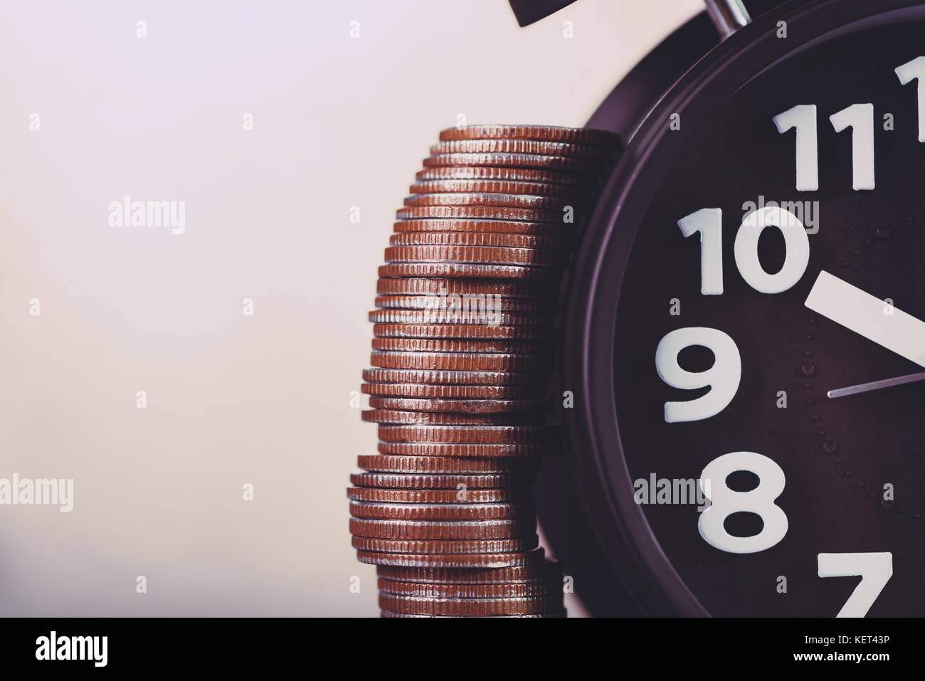 Alarm clock and piles of coin on working table, time for savings money ...