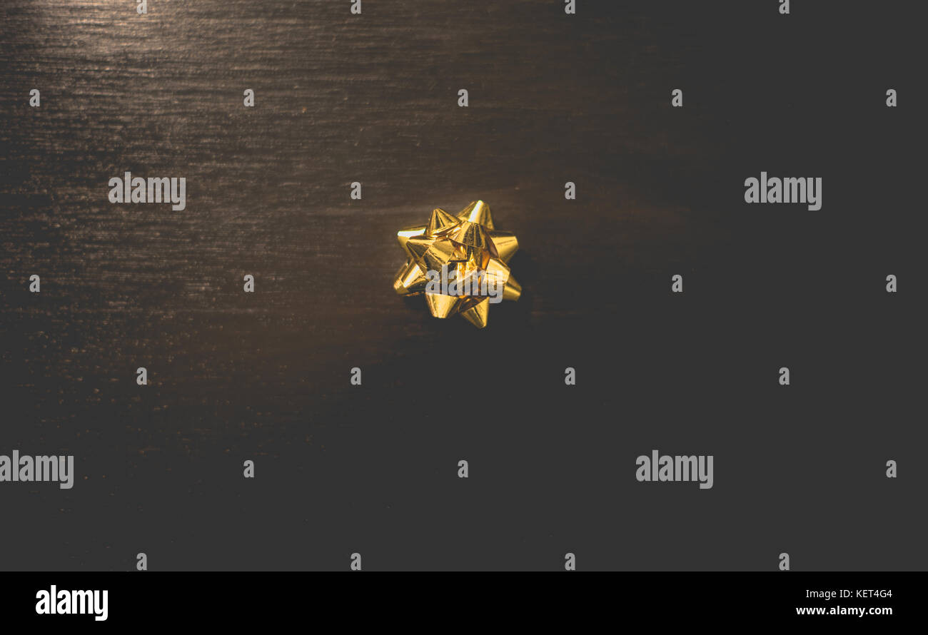 Tiny gold bow on brown desk surface Stock Photo - Alamy