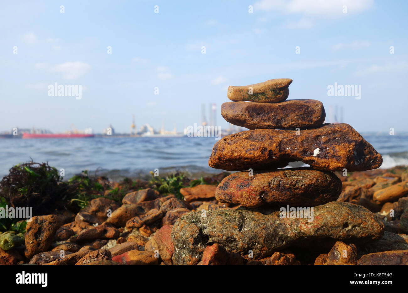 Rocks on the coast of the sea with shipyard as background Stock Photo ...
