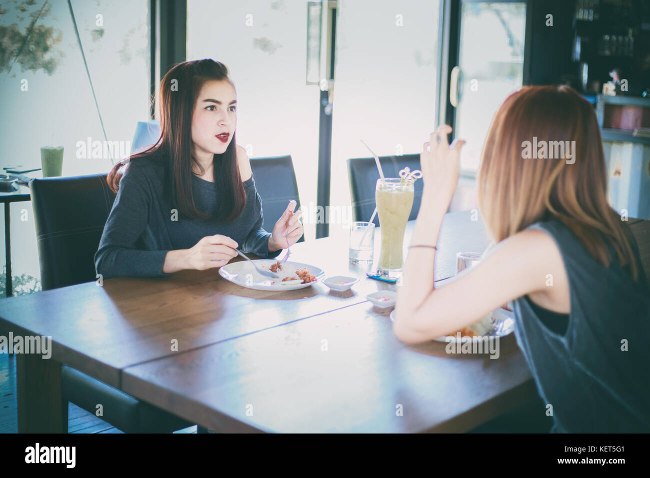 Two young female friends laugh and Having Lunch Together At Restaurant ...