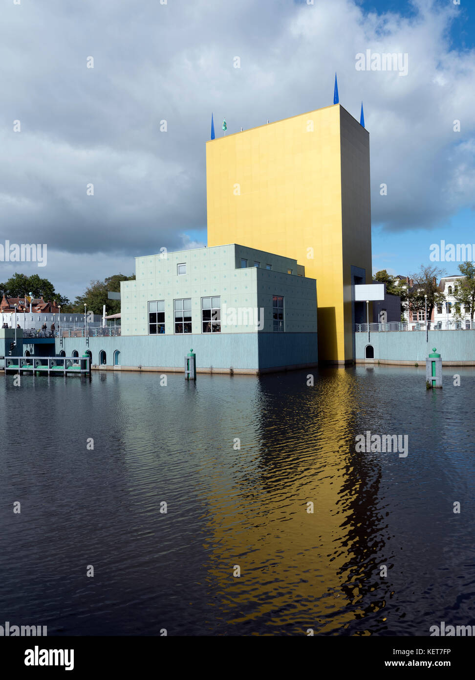 yellow tower of groninger museum in groningen reflected in water of ...