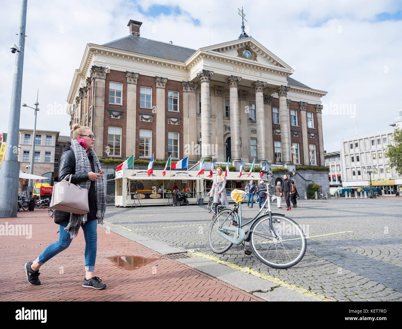 woman with mobile phone passes city hall of groningen in the ...